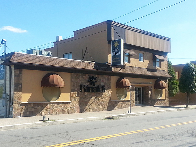 The welcoming façade of Cafe Rinaldi beckons with its stone exterior and distinctive burgundy awnings – Old Forge's culinary beacon on a cloudy Pennsylvania day.