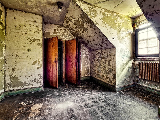 Time stands still in this eerie patient room, where peeling walls and weathered wooden doors whisper stories of a bygone institutional era.