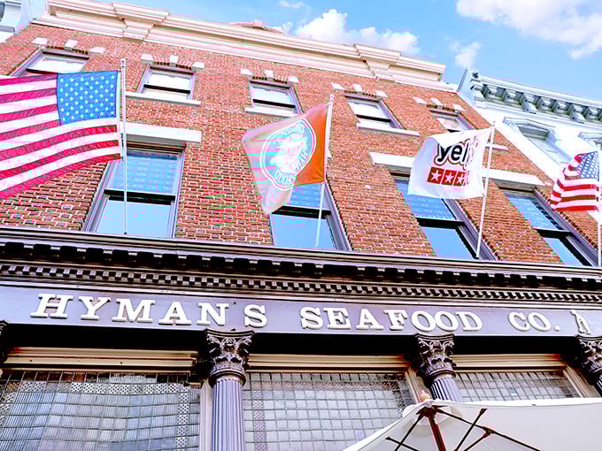 The historic brick façade of Hyman's Seafood stands proudly on Meeting Street, flags waving like a maritime welcome committee for hungry visitors.
