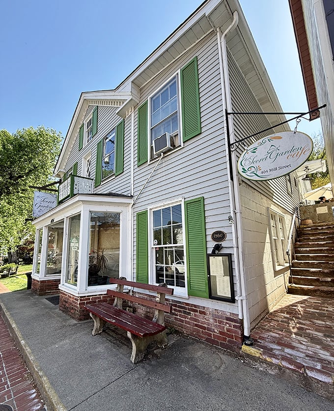 Perched on Mill Street like a culinary lighthouse, the cafe's hanging sign promises garden delights while the weathered bench offers a moment to savor the anticipation.