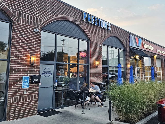 Twilight at Preston's – when the neon sign glows and hungry pilgrims gather for their burger benediction. The brick archways welcome all seekers of smashed-patty perfection.