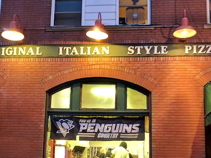 The iconic brick façade of Police Station Pizza glows warmly at dusk, its "Original Italian Style Pizza" sign a beacon for hungry Pennsylvanians.