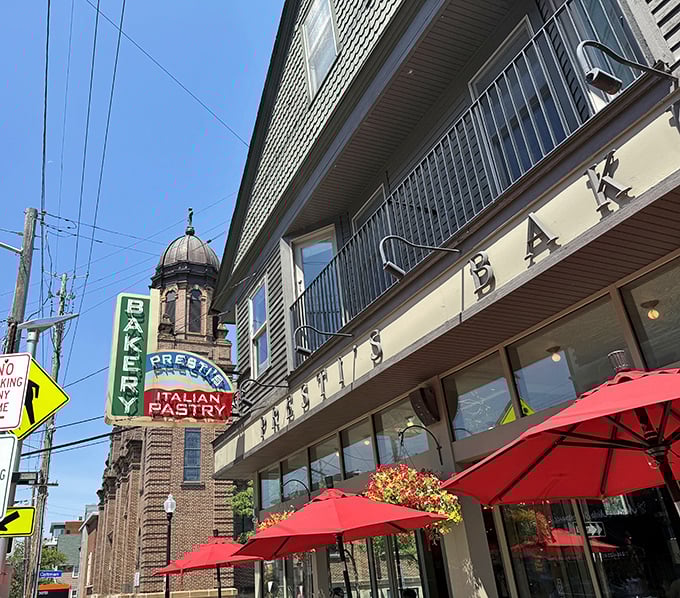 The iconic vertical "BAKERY" sign has guided hungry pilgrims to this Little Italy landmark for generations. Red umbrellas promise sweet shelter for pastry enthusiasts.
