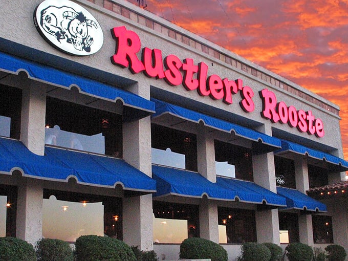 The iconic Rustler's Rooste sign glows against an Arizona sunset, promising Western adventures and hearty meals that await inside.