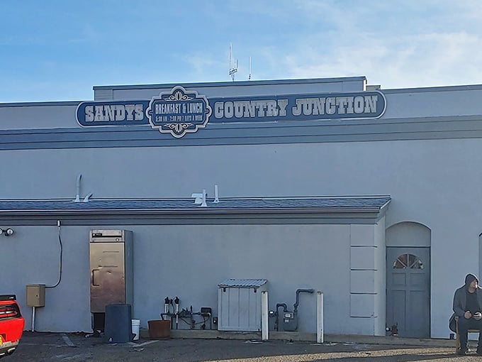 The white-washed exterior of Sandy's Country Junction welcomes hungry travelers with rustic charm and a shaded patio that practically whispers, "Come sit a spell."