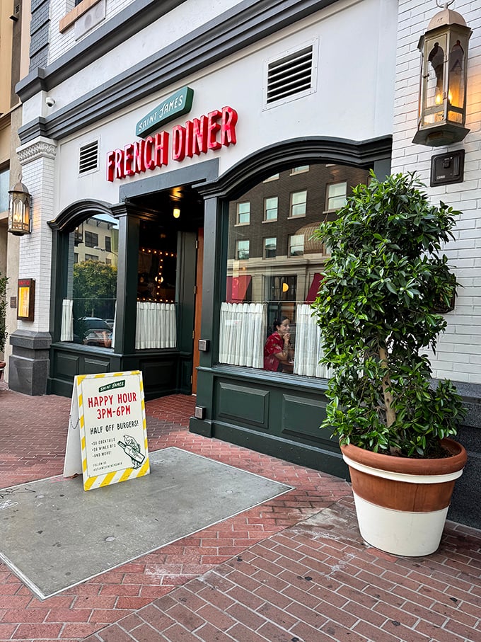 The red neon "FRENCH DINER" sign beckons like a lighthouse for the food-obsessed. Classic white brick, green trim, and that happy hour sign promising half-price burgers—resistance is futile.