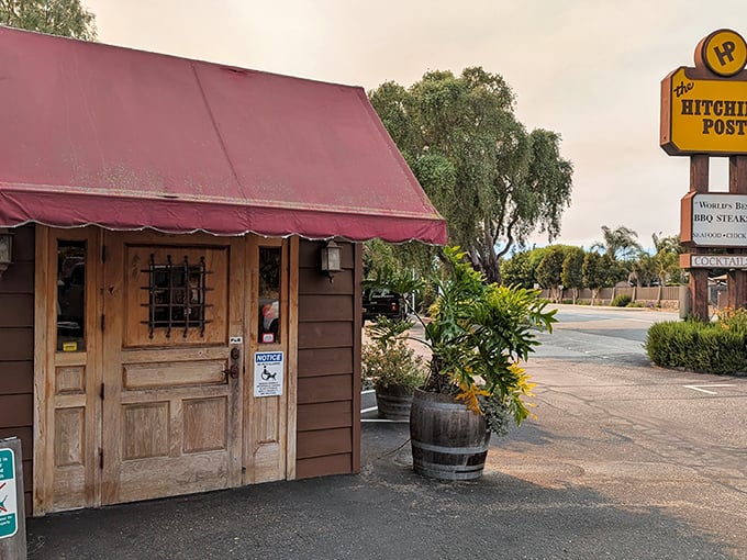The unassuming exterior of Hitching Post 2 proves once again that culinary greatness often hides behind modest facades. That burgundy awning has sheltered countless food pilgrims.