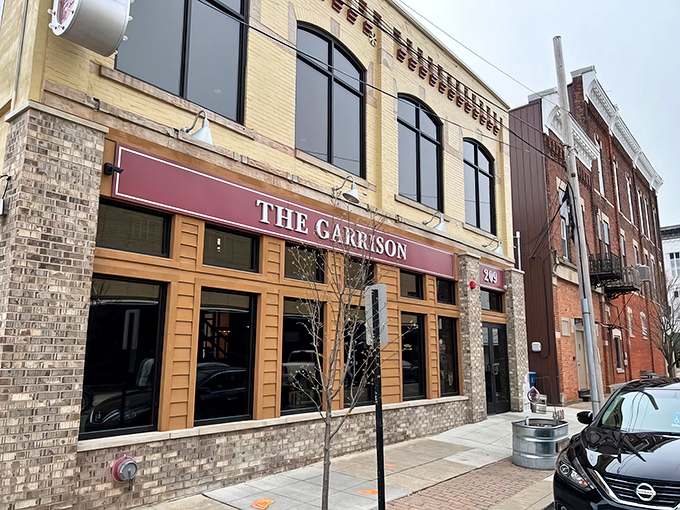 The golden-bricked façade of The Garrison stands like a culinary fortress on Fremont's Garrison Street, its burgundy awning beckoning hungry travelers inside.