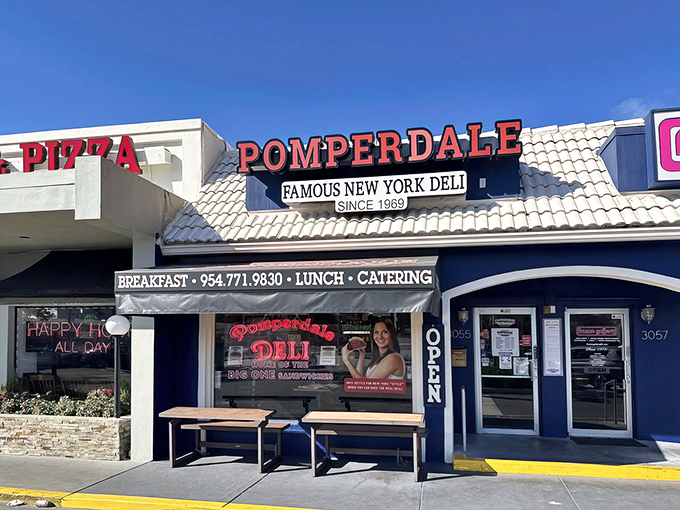 The blue-and-white facade of Pomperdale stands like a delicious mirage in the Florida sunshine, promising authentic New York deli treasures inside.