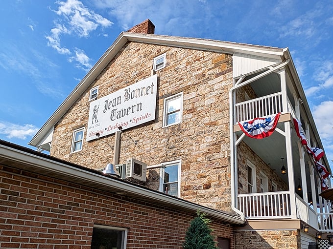 The tavern's exterior showcases Pennsylvania fieldstone craftsmanship that's outlasted empires, with patriotic bunting adding a touch of stars-and-stripes charm.