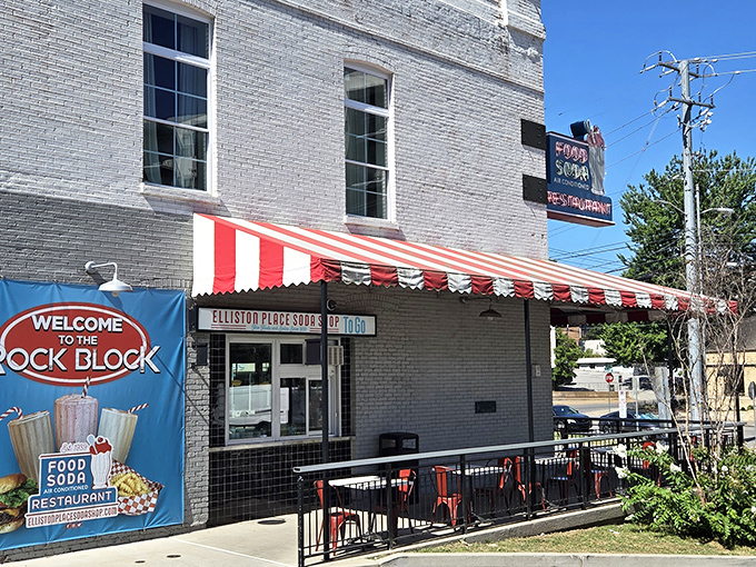 The iconic red and white striped awning of Elliston Place Soda Shop beckons like a time machine disguised as a restaurant in Nashville's Rock Block.