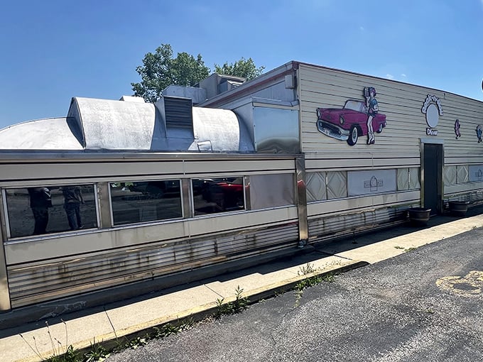 The classic aluminum exterior of Nancy's Main Street Diner gleams in the sunlight, complete with vintage car artwork that promises a journey back to simpler times.