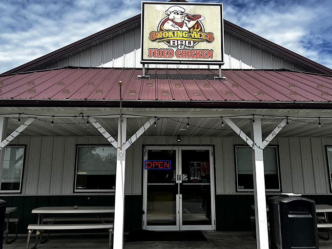 The humble white building with its burgundy roof might not look fancy, but that cartoon pig in sunglasses knows something you don't—barbecue paradise awaits inside.