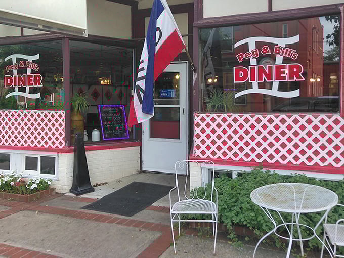 The welcoming entrance to Peg & Bill's Diner, where classic red lattice and an "OPEN" flag promise authentic Pennsylvania comfort food inside.