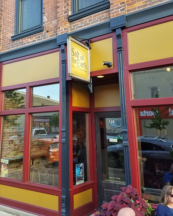 The bright yellow and burgundy facade of Salt of the Earth stands like a beacon of culinary promise on Fennville's Main Street, inviting hungry travelers to step inside.