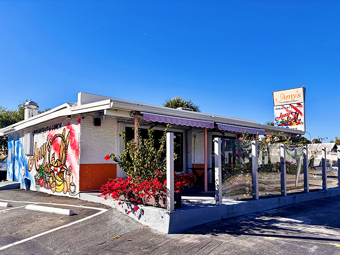 A splash of orange and white with a colorful mural welcomes you to this unassuming French oasis in Pompano Beach.