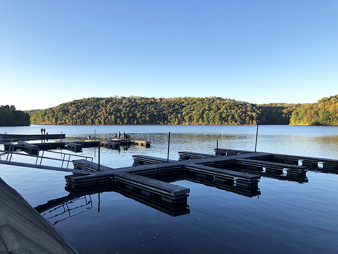 Tranquility perfected: Salt Fork Lake’s glassy surface mirrors the forested hills, while visitors linger along the shore to savor the peaceful view.