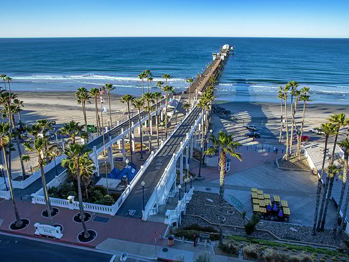 Oceanside's iconic pier stretches toward infinity like a wooden runway to paradise, palm trees standing guard as if to say, "Yes, this view is actually real."