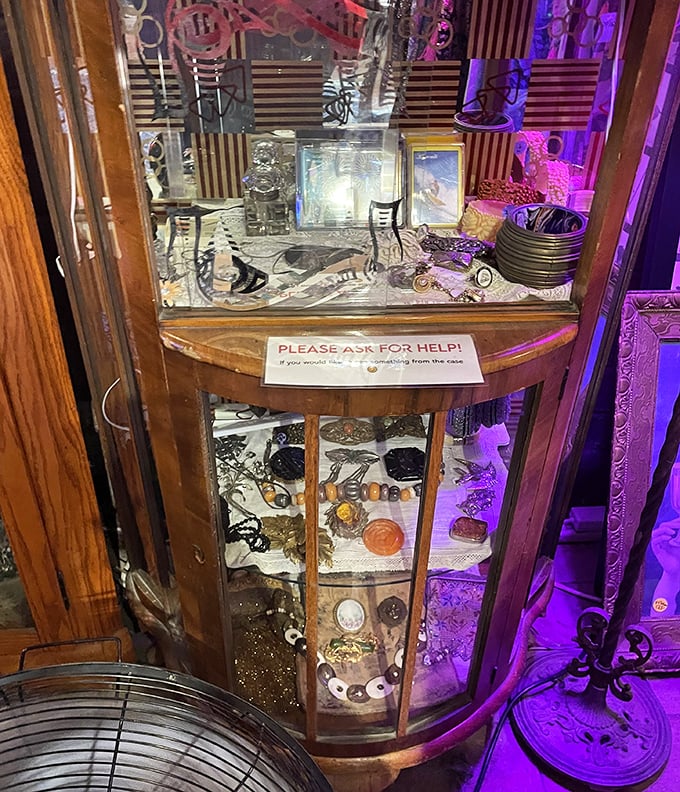 Purple lighting transforms ordinary jewelry displays into treasure chests with a sign politely requesting help—because some treasures require guidance.