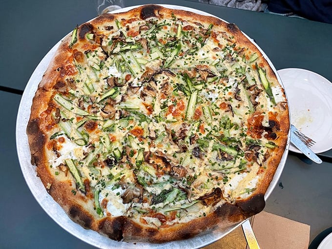 The asparagus pizza demonstrates that vegetables deserve their moment in the wood-fired spotlight too—a springtime symphony on dough.