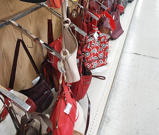 A crimson collection of handbags dangles like ripe fruit, each one holding the potential to become someone's "Can you believe I thrifted this?" story.