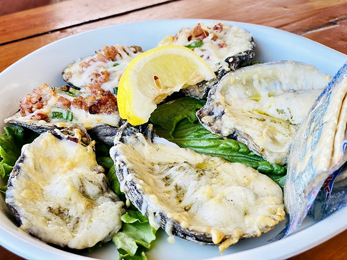 Baked oysters resting on a bed of greens with a bright lemon accent – nature's perfect appetizer getting the respect it deserves.