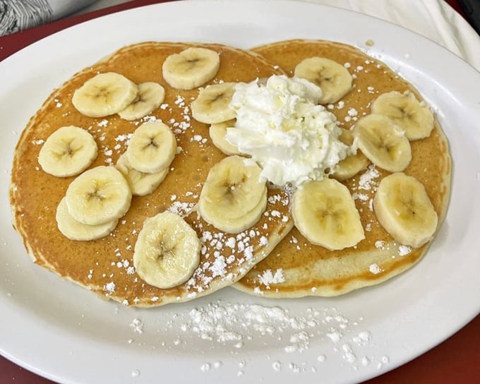Banana pancakes with a cloud of whipped cream—proof that sometimes the simplest pleasures are just a spatula flip away from perfection.