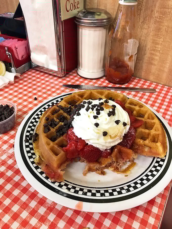 Waffles that make you question every other breakfast you've ever had—crisp exterior, fluffy interior, and topped with a cloud of whipped cream and fresh berries.