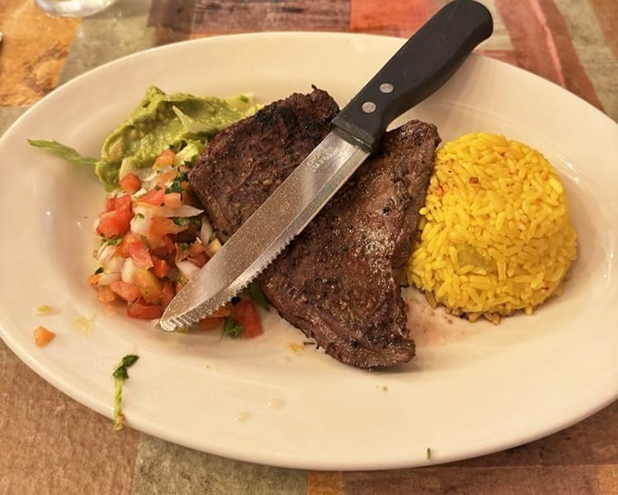 This carne asada isn't messing around – perfectly seasoned beef flanked by fresh guacamole, pico de gallo, and golden rice that demands your full attention.