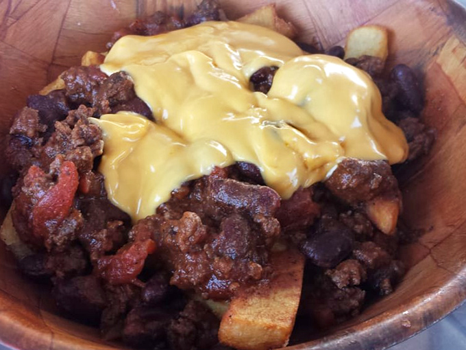 A wooden bowl of meaty chili topped with melted cheese – comfort food that speaks a universal language.