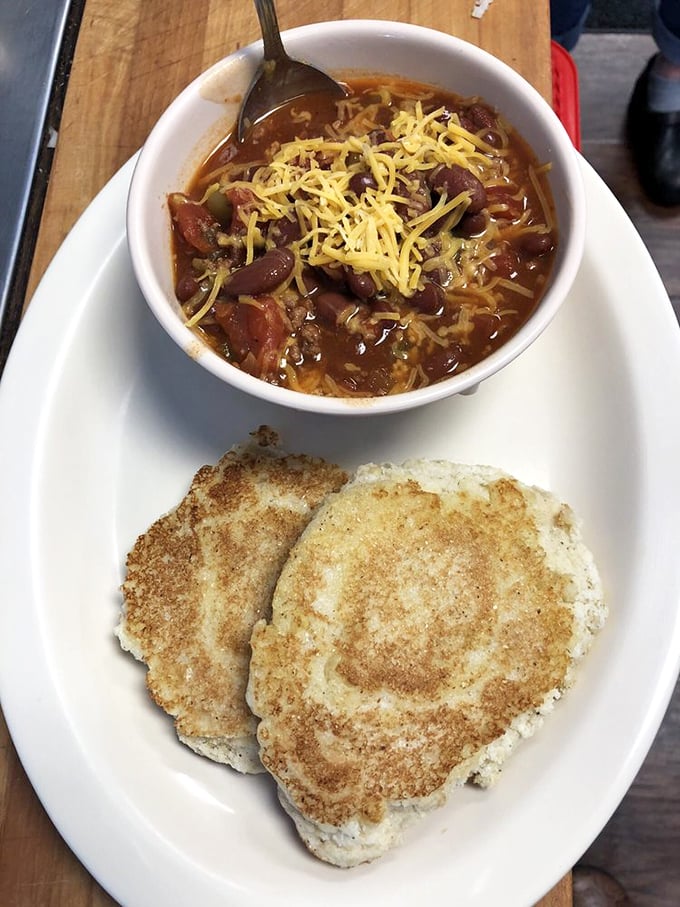Chili topped with melted cheese alongside cornbread – a bowl of warmth that makes even the worst Monday feel like a Friday afternoon.