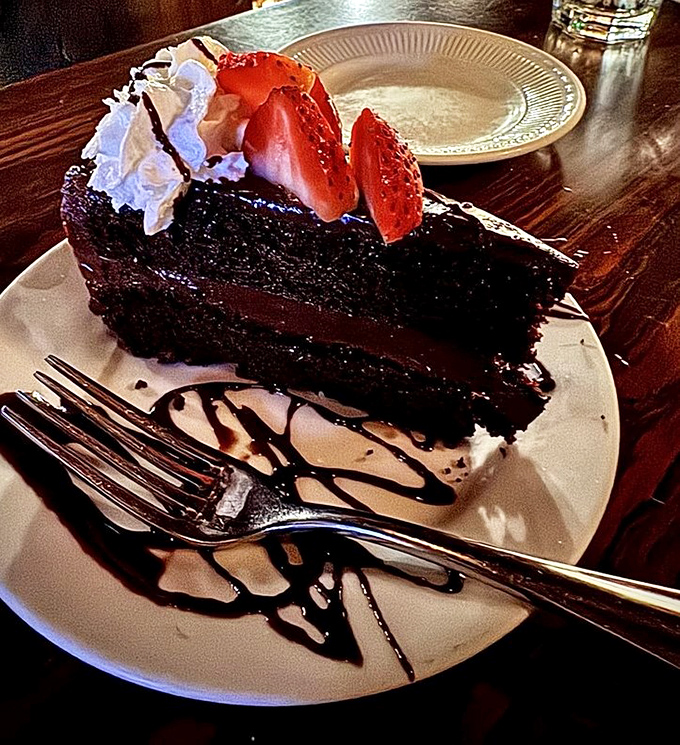 Chocolate cake so decadent it should require a permission slip, topped with strawberries pretending to make it somewhat virtuous.