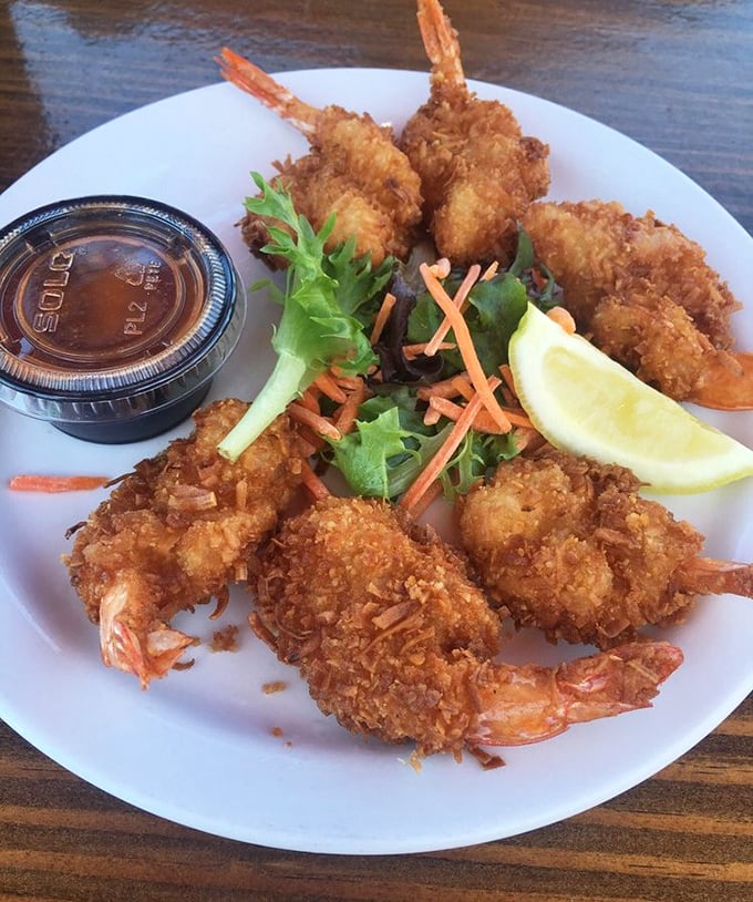 Coconut shrimp with tails reaching skyward like they're still trying to escape. That golden crust practically audibly crunches through the photo. 