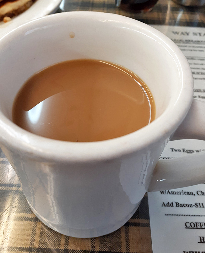 Coffee in a sturdy white mug – no pretentious vessels here. This is the kind of honest brew that fuels conversations and cures Monday mornings.