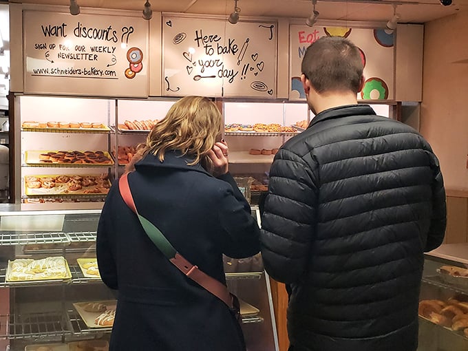 The universal language of indecision: two customers contemplating which delicious carbohydrate masterpiece will accompany their morning coffee.