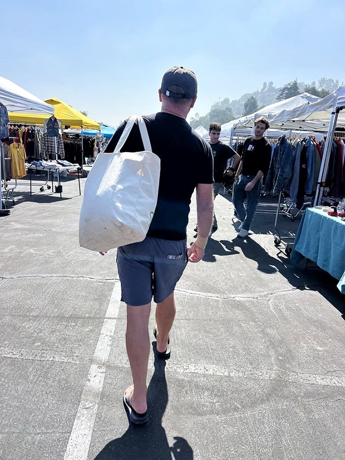 The white tote bag—unofficial uniform of serious flea market warriors. This gentleman has clearly come prepared for significant discoveries.