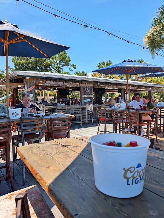 The outdoor deck—where strangers become friends and cold beverages taste twice as good under those signature blue umbrellas.