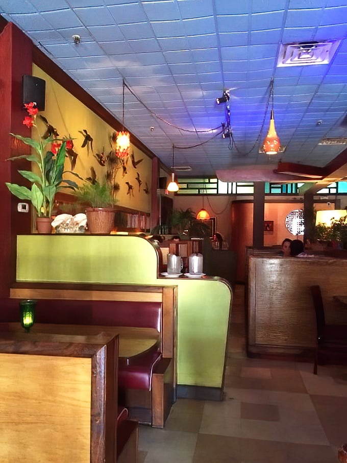 Wooden booths and ambient lighting create dining spaces that feel like your own private nook in this botanical-meets-bohemian restaurant.