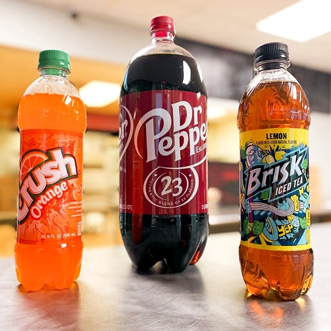 The holy trinity of fountain drinks stands ready to wash down your pizza feast. Orange Crush, Dr. Pepper, and Brisk – the perfect pizza companions.
