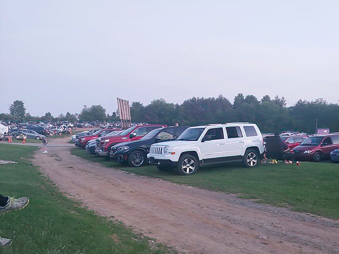 Vehicles line up in neat rows, each a personal theater pod where dress codes are optional and comfort is mandatory.