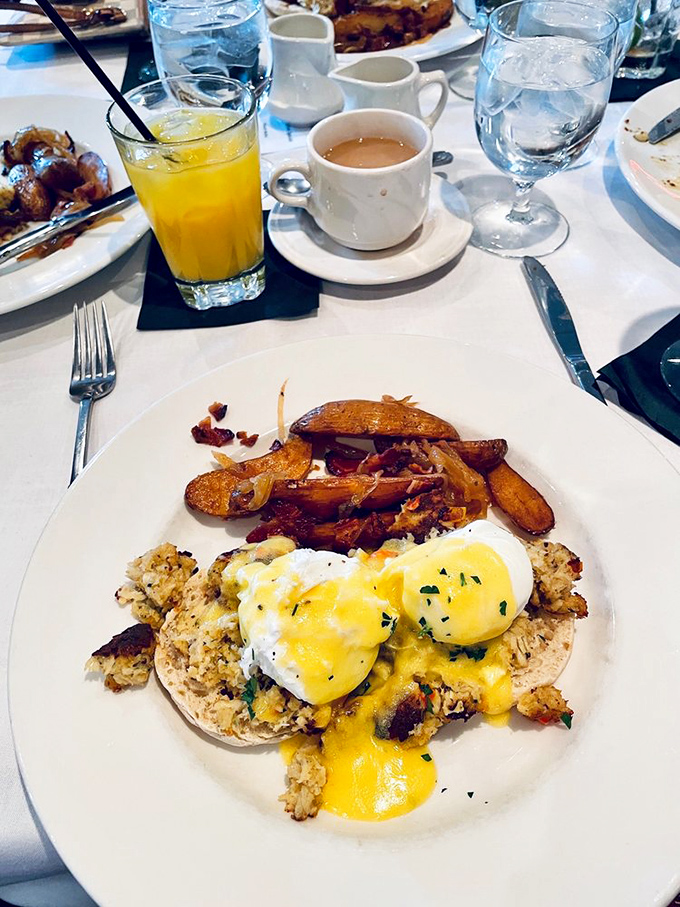 Brunch perfection: poached eggs draped in hollandaise atop what appears to be crab cakes, with potatoes on the side for good measure.