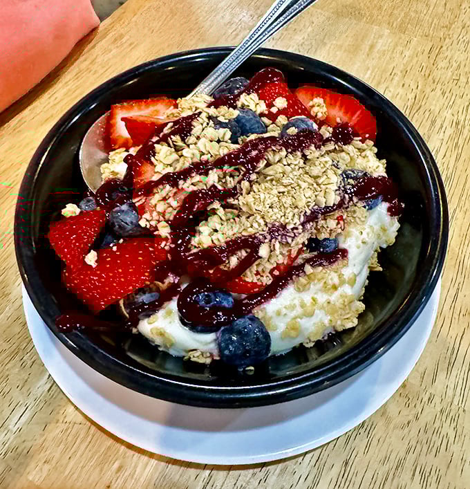 Not just yogurt and berries—a morning parfait of possibilities. The granola adds crunch while berry sauce drizzles down like sweet rain on a summer day.