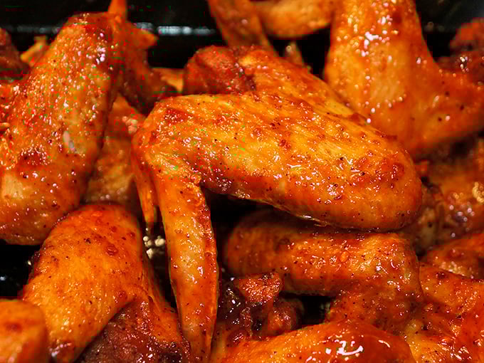 Glazed chicken wings glistening with sweet-spicy sauce—the kind that leave your fingers sticky and your taste buds begging for more.