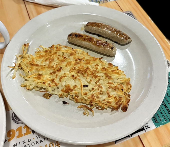 Crispy hash browns and sausage links – proof that sometimes the simplest breakfast combinations are culinary poetry on a plate.