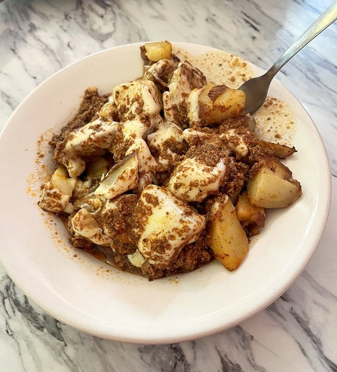 Home fries smothered in what appears to be a savory meat sauce—potatoes living their best, most indulgent life.