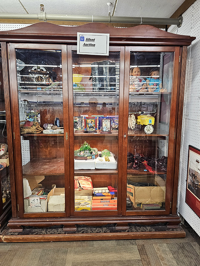 The silent auction cabinet showcases special treasures deemed too valuable for regular shelving. One person's donation becomes another's cherished collectible.