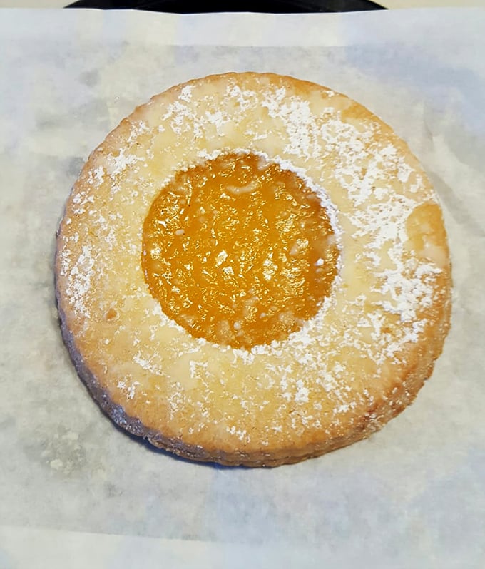 The lemon shortbread cookie—sunshine in edible form, dusted with powdered sugar like the first perfect snowfall of winter.