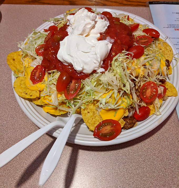 Nachos that require a strategy to eat – a mountain of chips, cheese, tomatoes, and sour cream that's worth every messy bite.