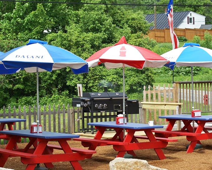 Summer dining at its finest—red picnic tables under patriotic umbrellas where the only thing better than the food is the New Hampshire fresh air.