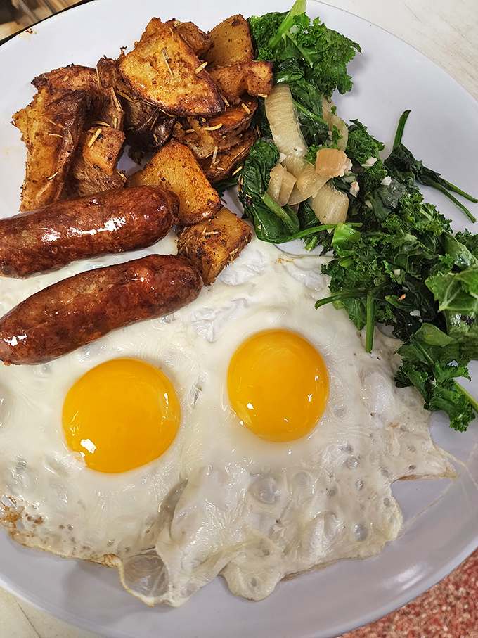 The breakfast platter that answers the eternal question: "Yes, you can have it all" – eggs, sausage, greens, and potatoes in perfect harmony.